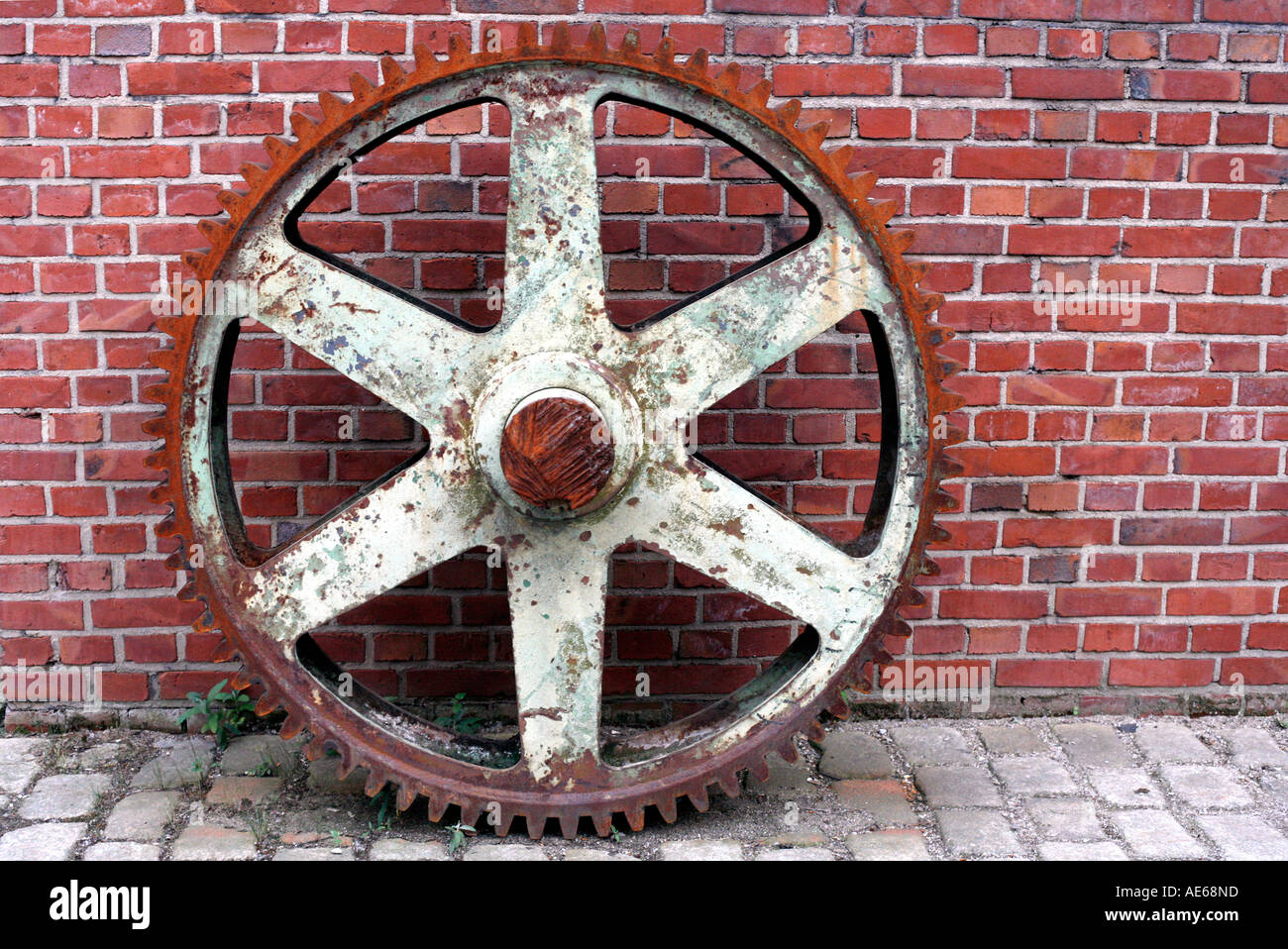 old rusted cog wheel in front of a brick wall Stock Photo - Alamy