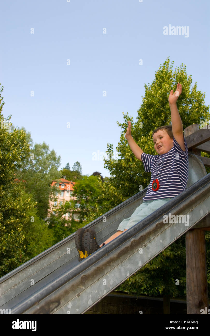 boy going down slide at playground Stock Photo - Alamy