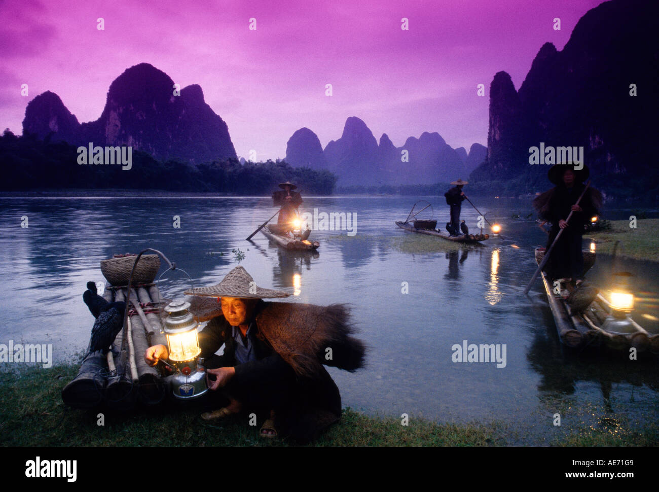 Li River cormorant fishermen on bamboo rafts lighting lanterns at dusk ...