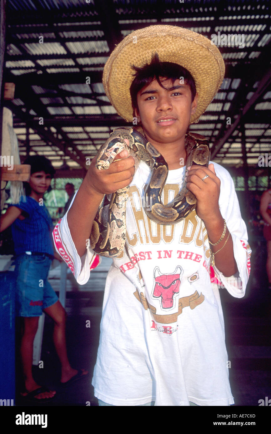 Native boy with python snake poses for tourists along the Amazon River ...
