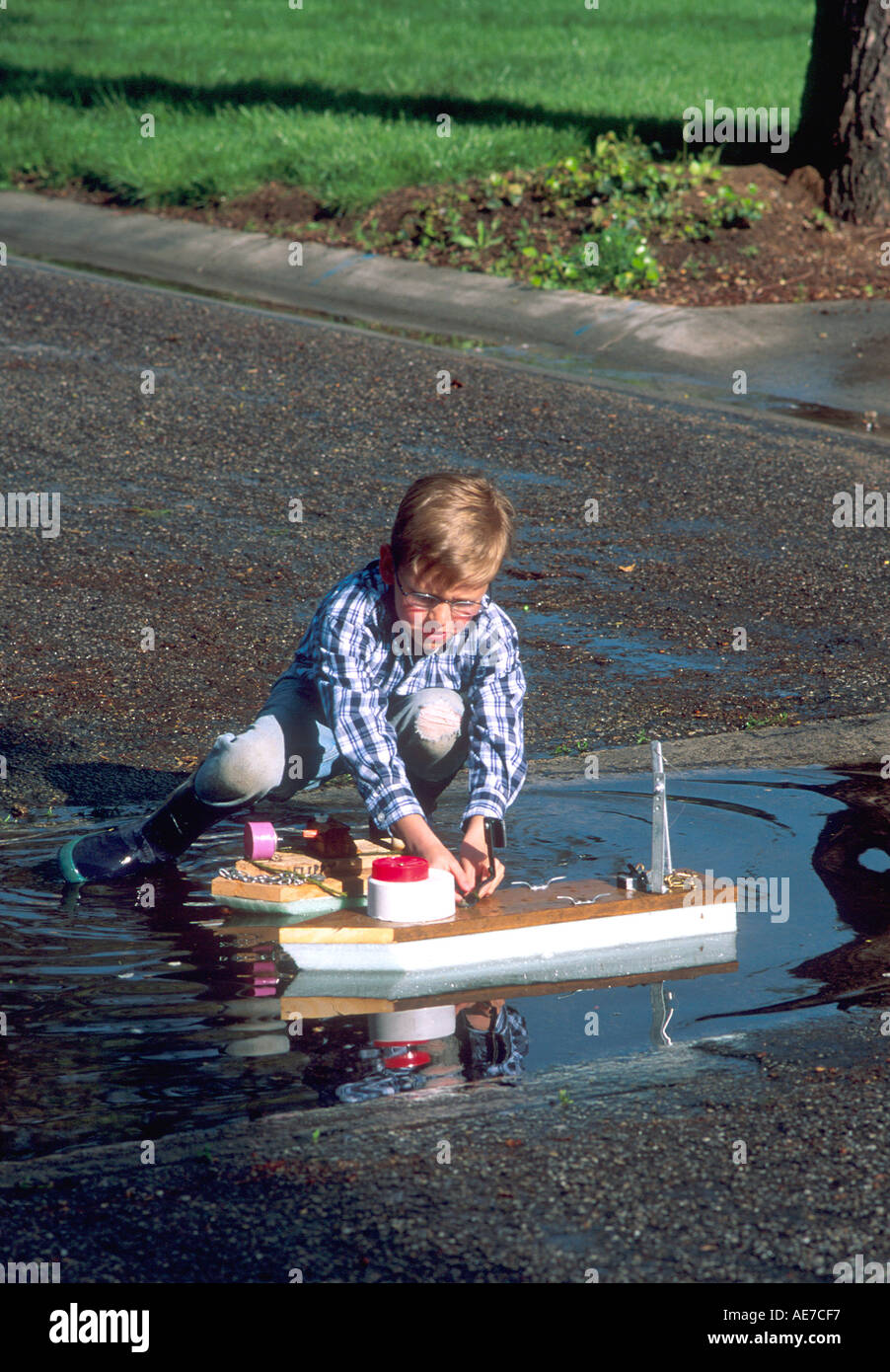 Six year old boy floating a home made model boat Stock Photo - Alamy