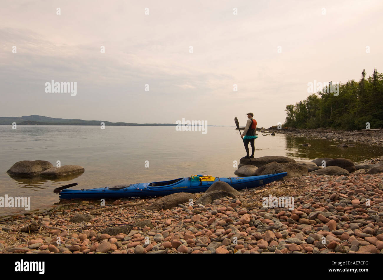 A SOLO KAYAKER STANDS ON A BOULDER ALONG PIGEON POINT MINNESOTA Stock ...