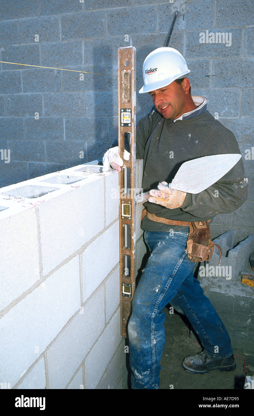 Mason using level to plumb up course with wall Stock Photo - Alamy