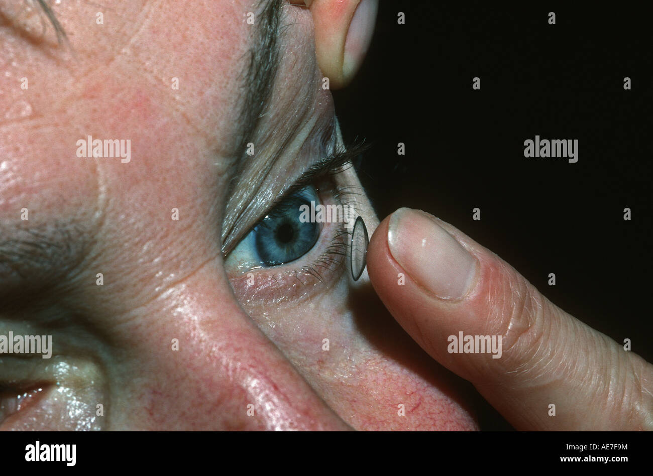 Finger placing contact lens over cornea of eye UK Stock Photo - Alamy