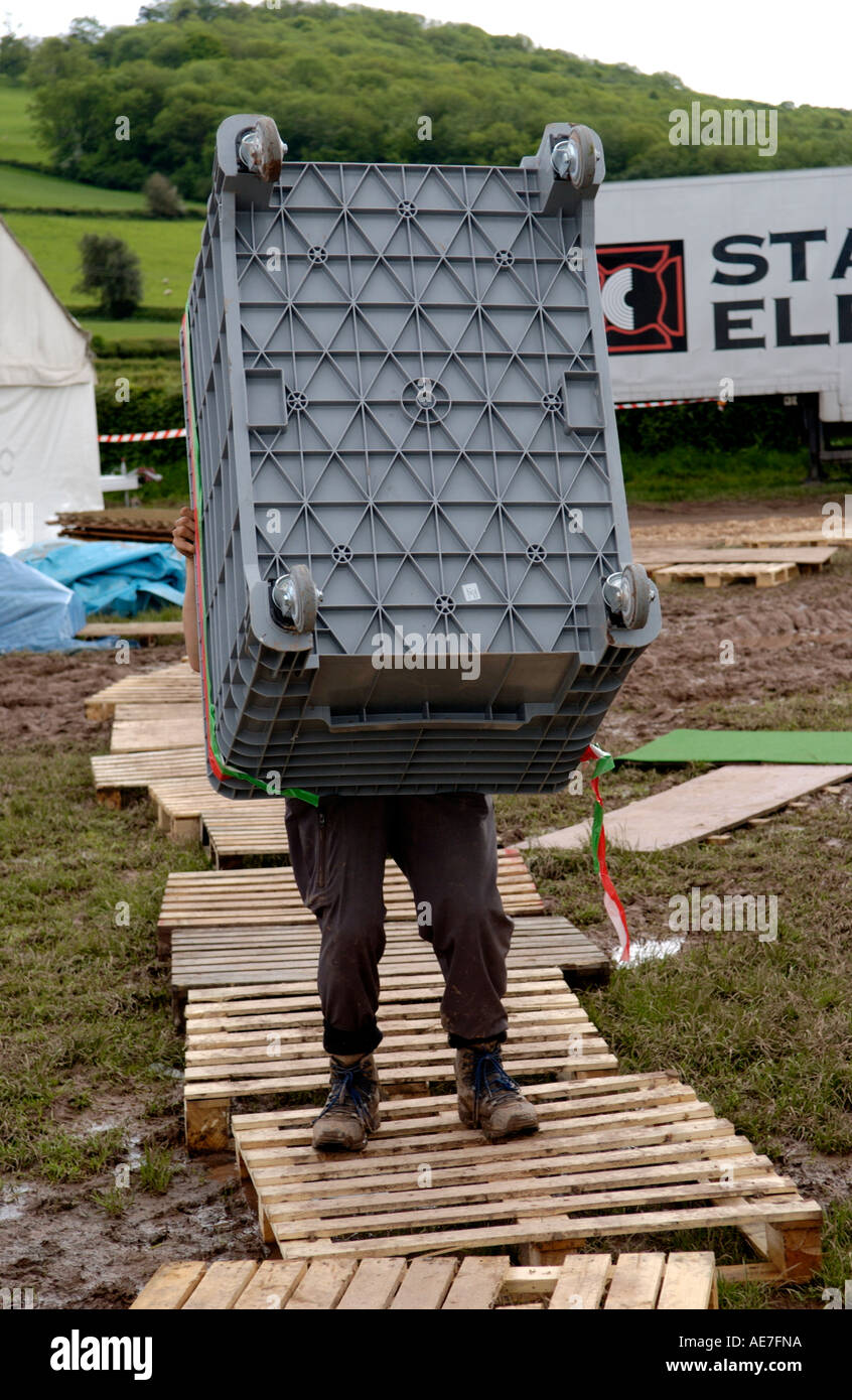 Man carrying crate on pallets over mud at Hay Festival Hay on Wye Powys ...