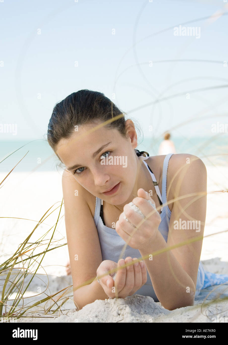 Girl lying on beach, letting sand run through hands Stock Photo - Alamy