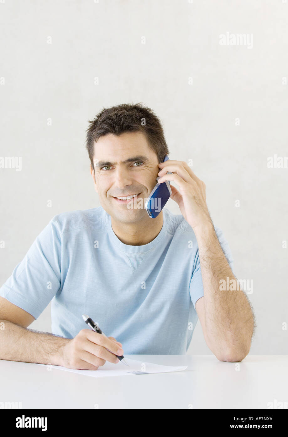 Man using cell phone and taking notes Stock Photo - Alamy