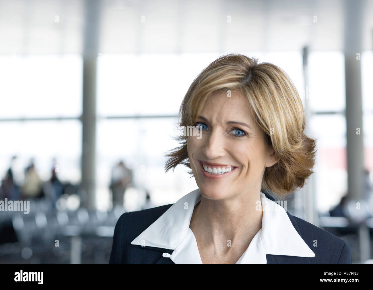 Woman in suit smiling in airport setting, portrait Stock Photo - Alamy