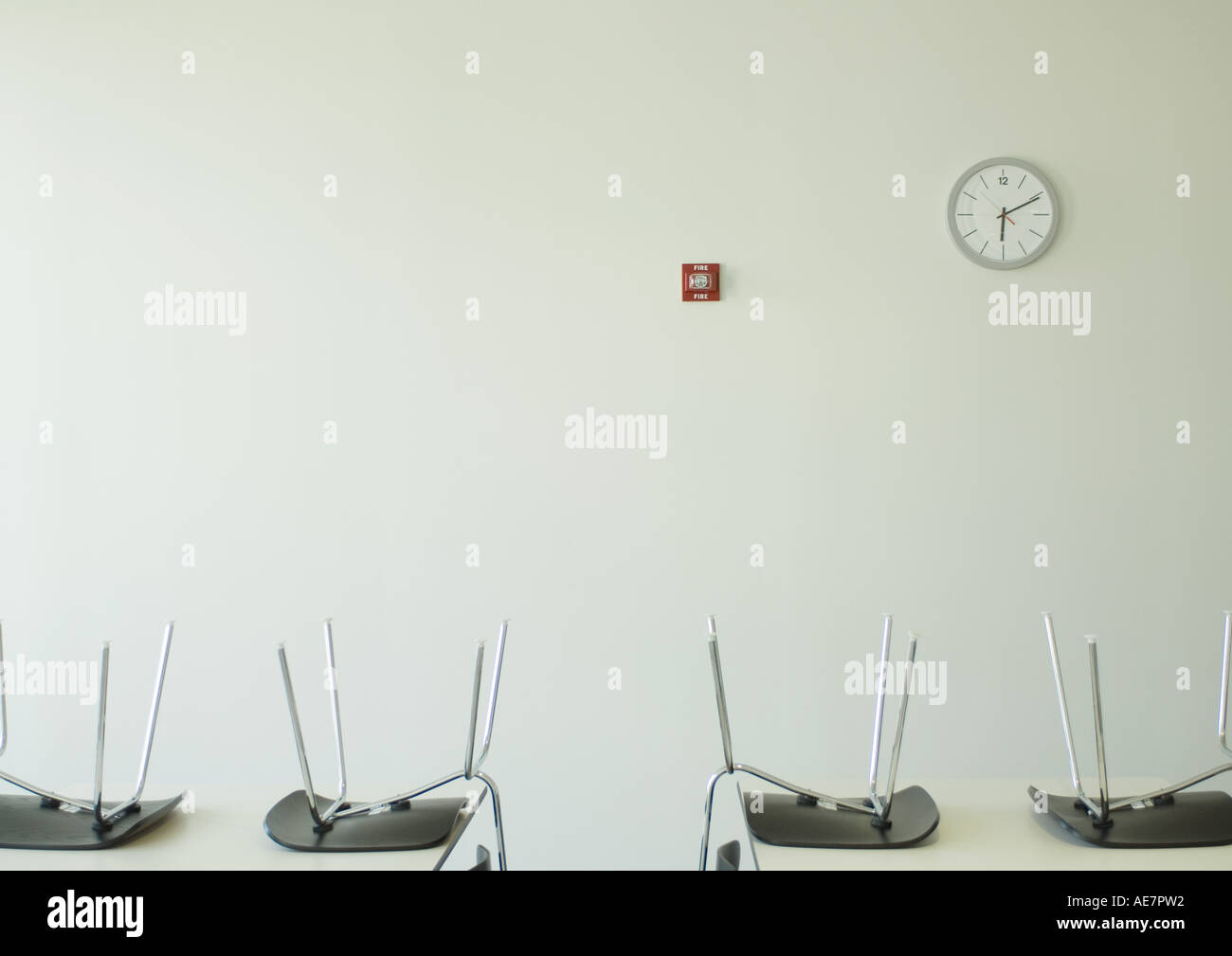 Chairs upside down on tables and clock on wall Stock Photo - Alamy