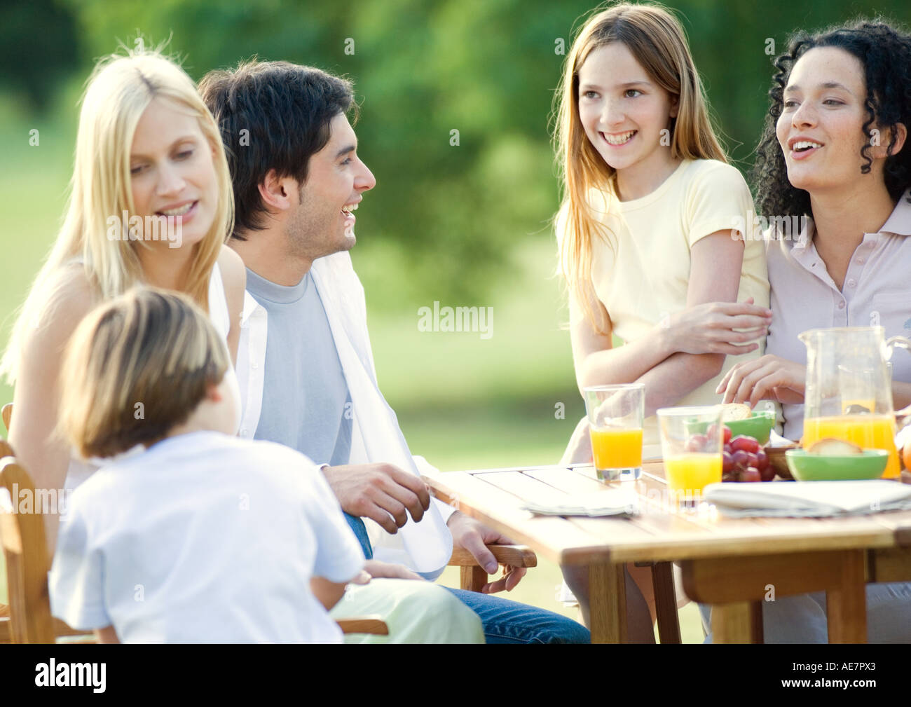 Family and kids sitting around table outdoors Stock Photo - Alamy
