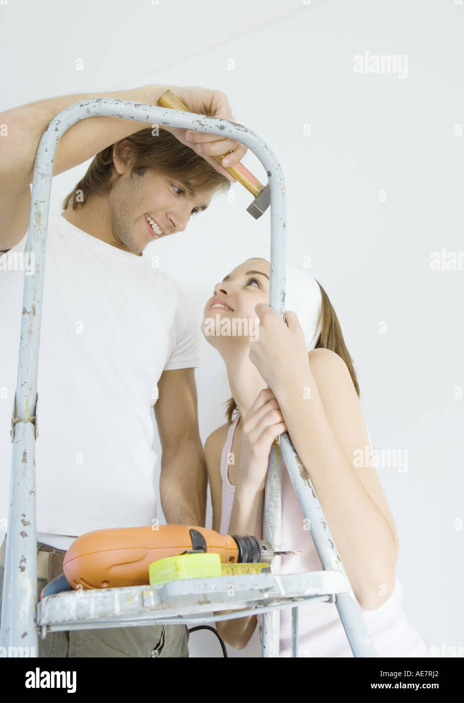 Couple with ladder and tools, smiling Stock Photo - Alamy