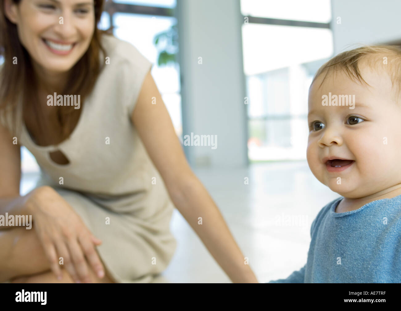 Woman smiling and watching baby Stock Photo - Alamy