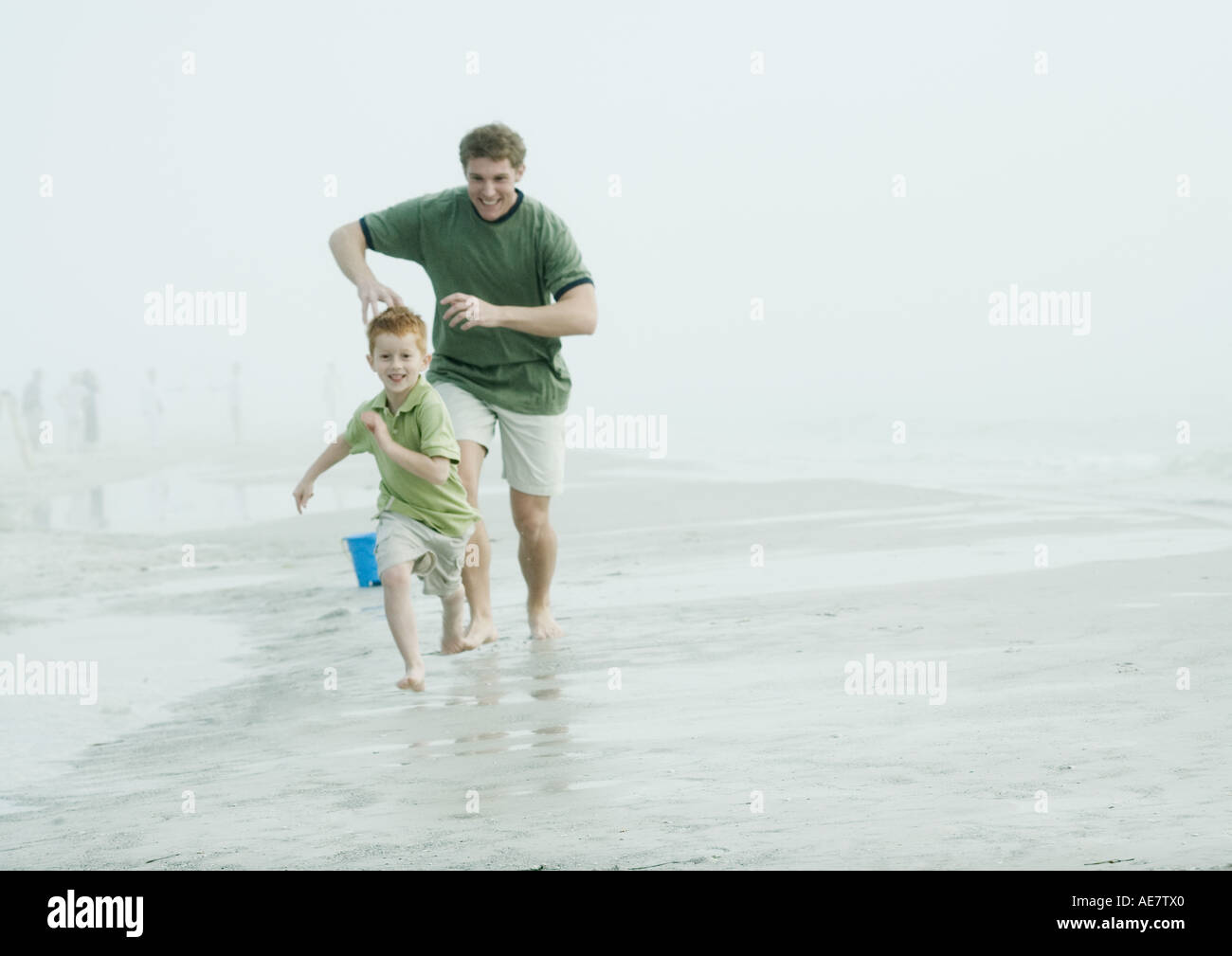 Man chasing son on beach Stock Photo - Alamy