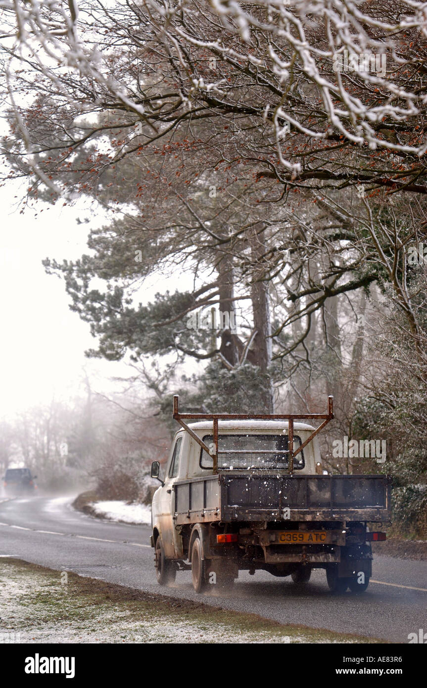 A TRUCK DRIVING PAST TREES WITH SNOW MELTING DURING A THAW UK Stock ...