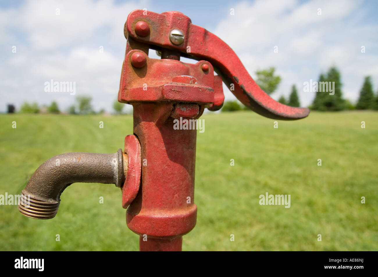 Red water pump isolated by a blurred park background Stock Photo - Alamy