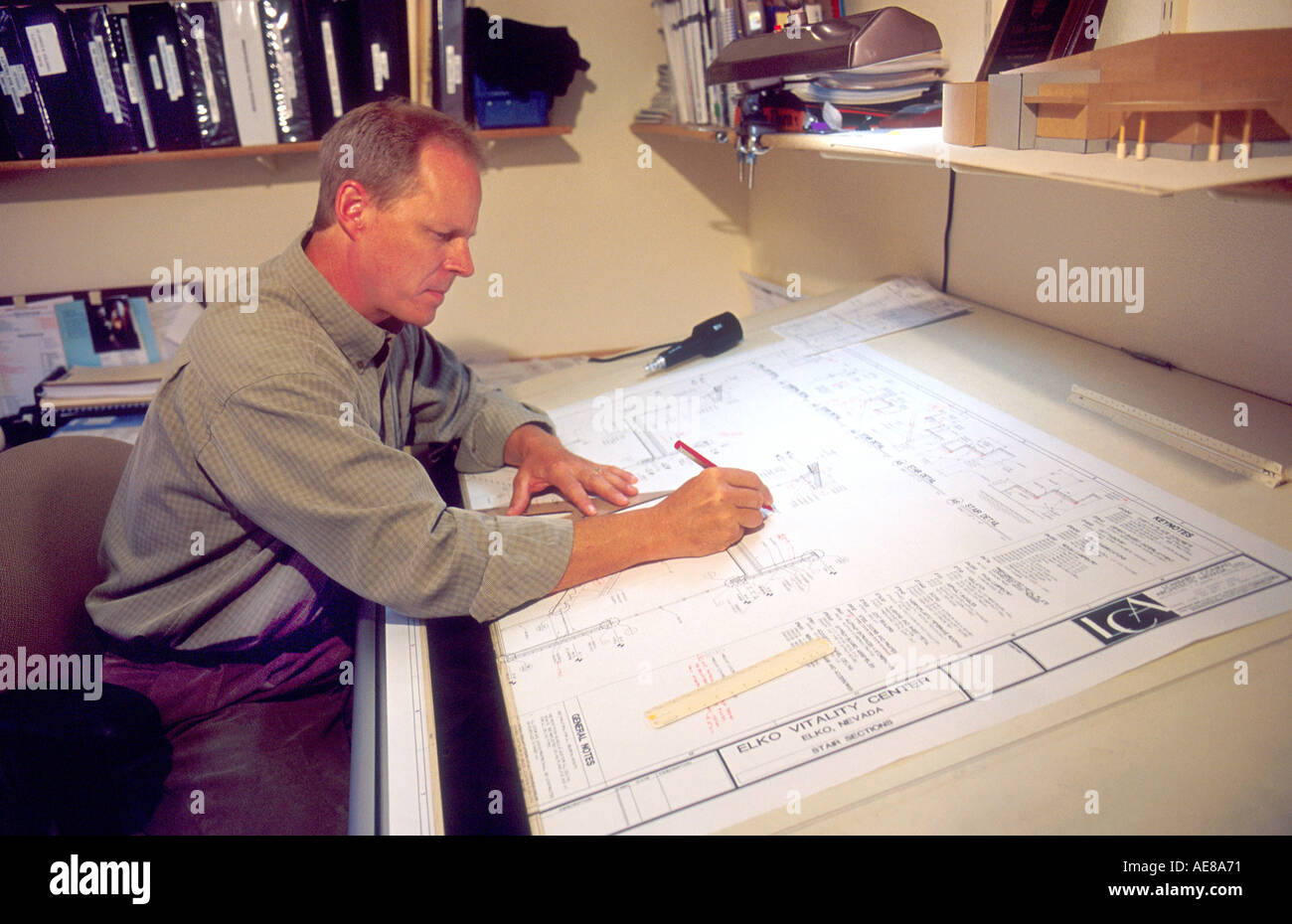 Architect using traditional drafting table examines blue prints Stock ...