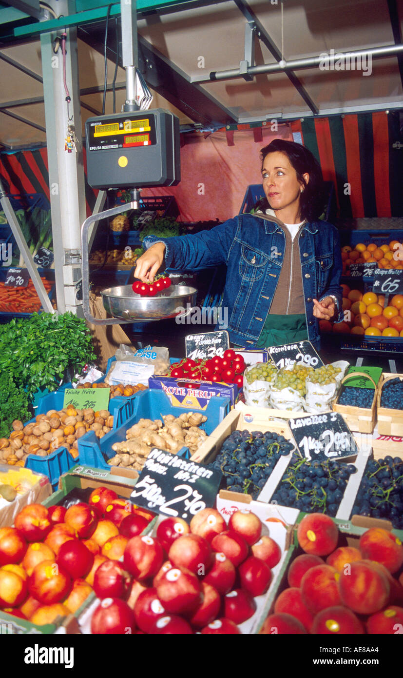 Outdoor produce market at Cologne Germany German woman weighs tomato ...