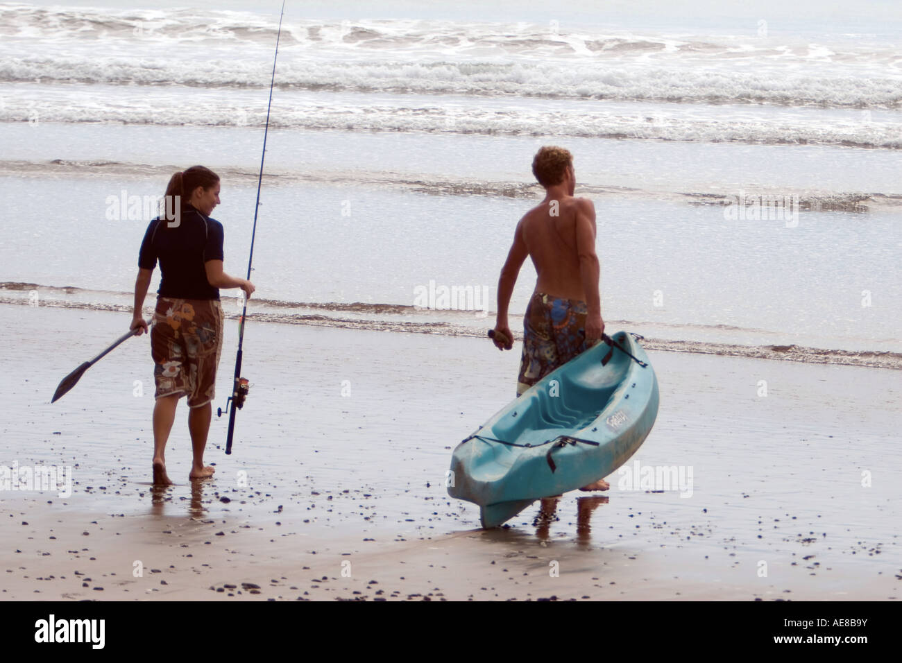 male and female walking with a ocean kayak Stock Photo - Alamy