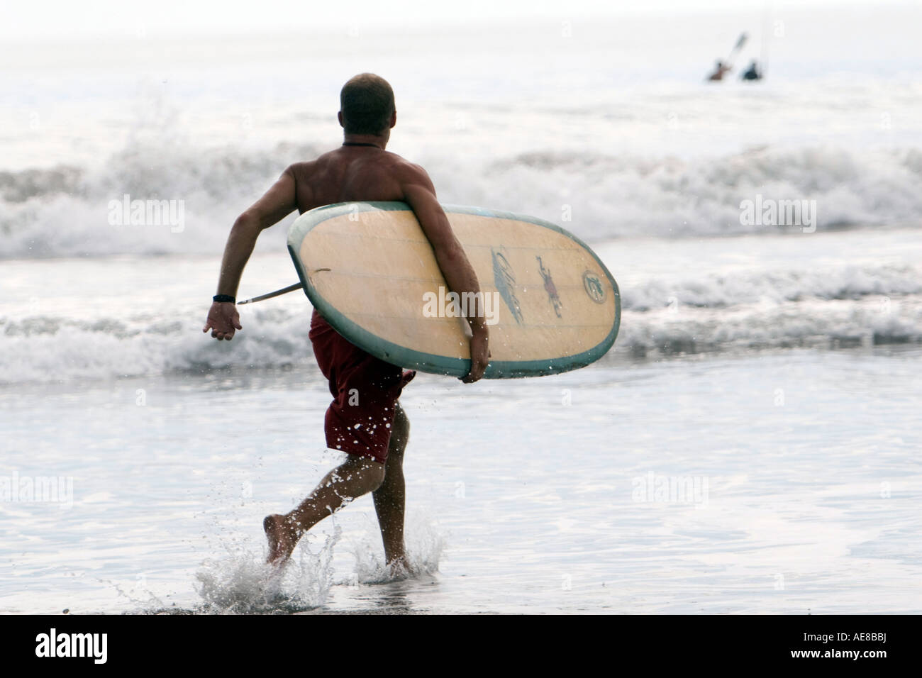 man running with a surf board Stock Photo - Alamy