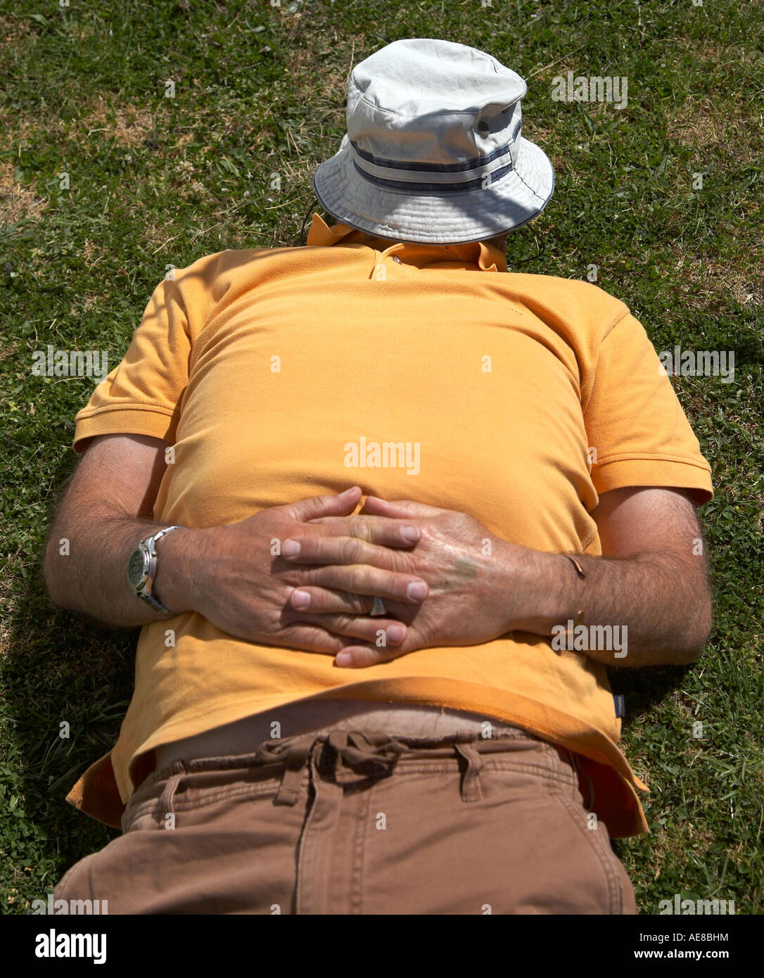 man laying on grass in the sun with floppy hat over his face Stock ...