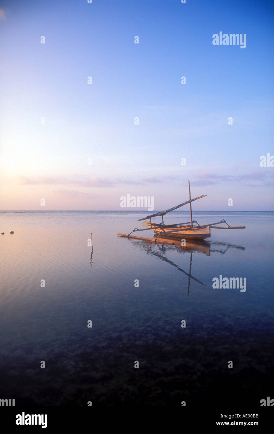 Traditional outrigger fishing boat at rest in calm water off of Lombok ...