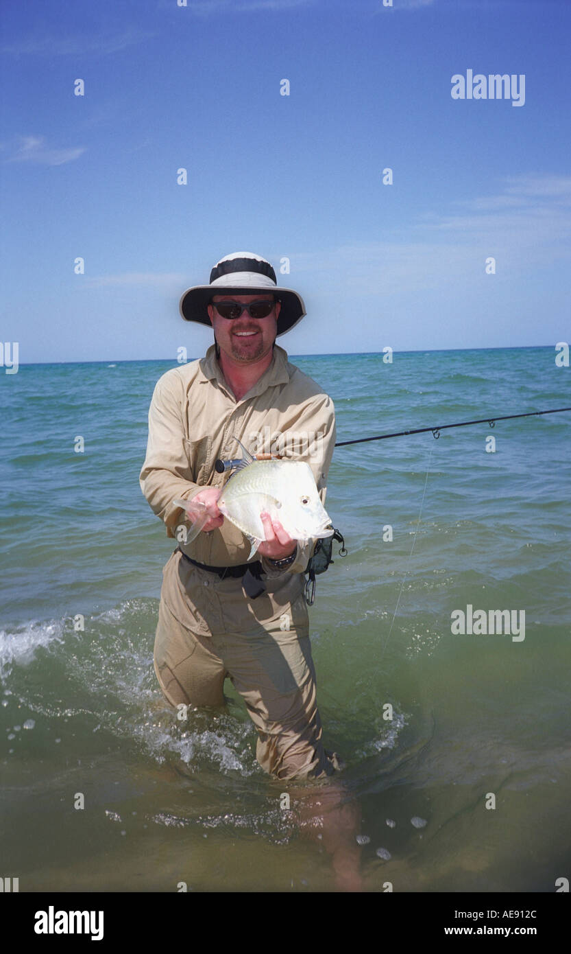 Man holding lookdown fish caught while fly fishing from the shoreline ...