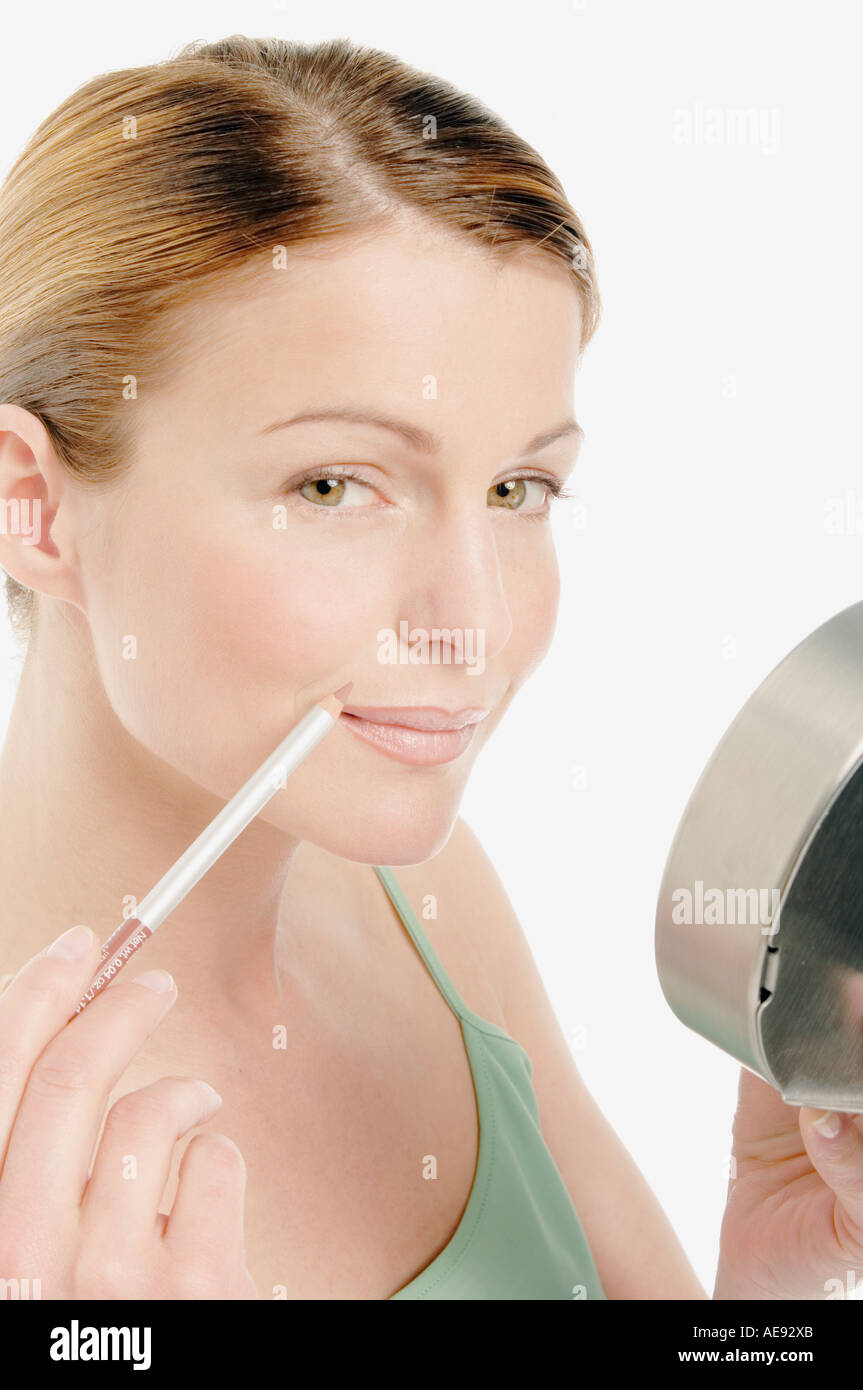 Young Woman face making-up her mouth with a pen, little mirror in her ...