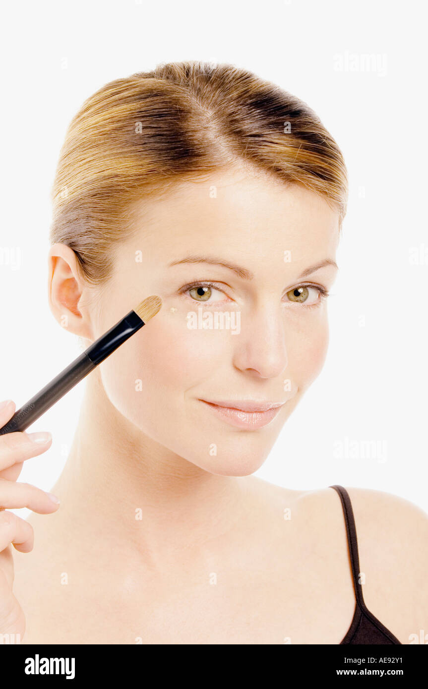 Young Woman face making-up with eyeshadow, drops of cream under her eye ...