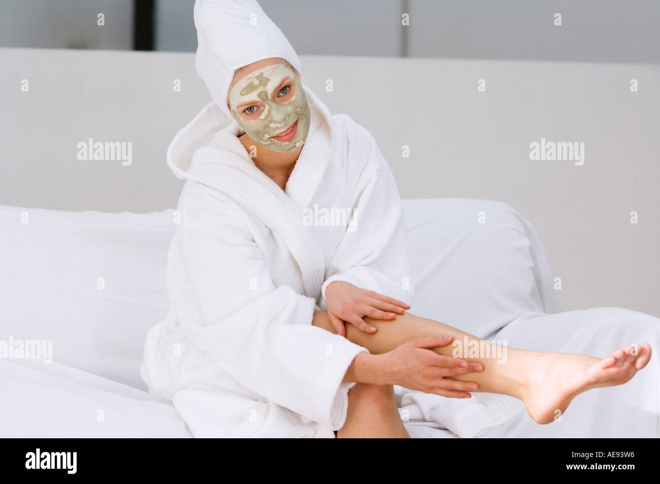 Young woman with beauty mask on her face, massaging her leg Stock Photo ...