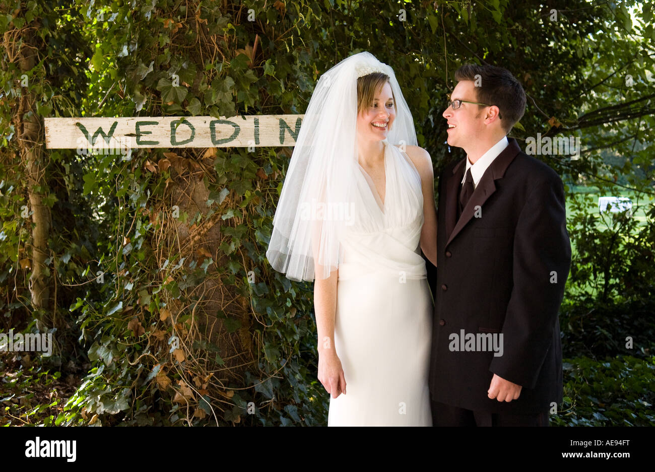 Bride and her groom standing next to a wedding sign Stock Photo - Alamy