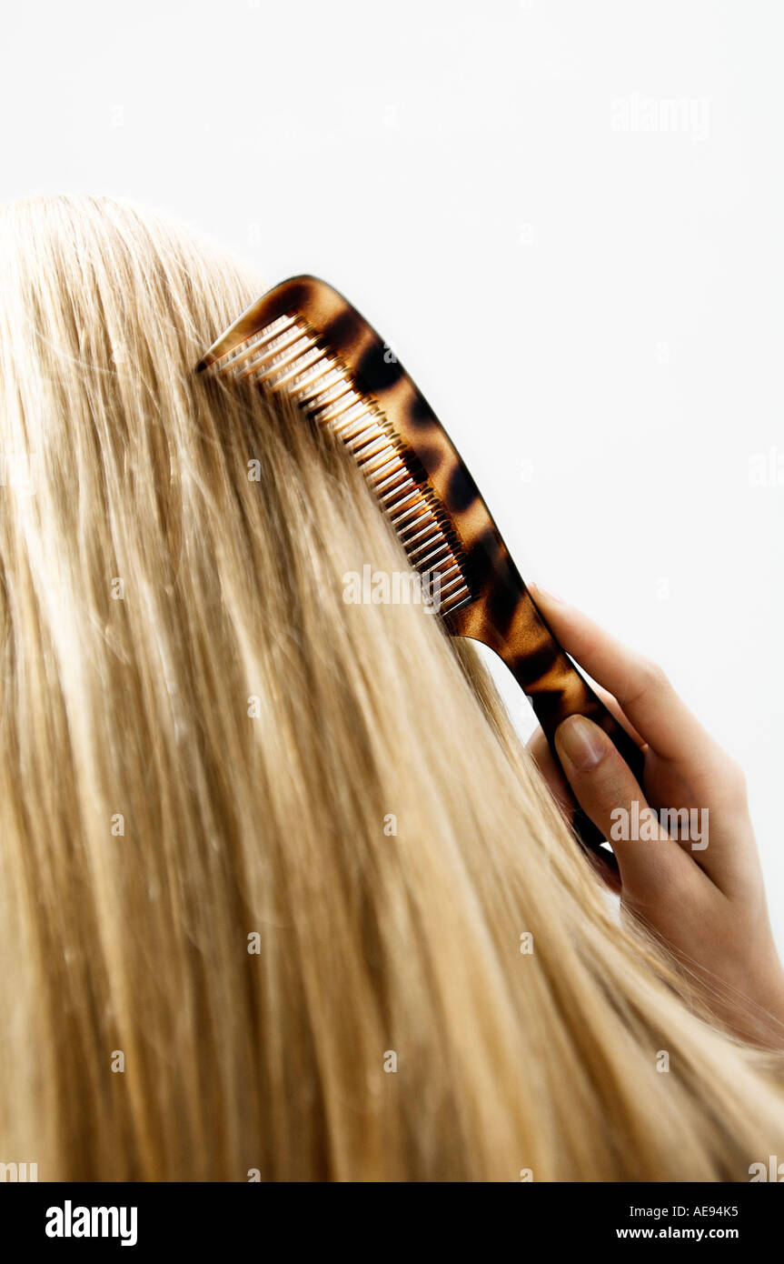 Portrait of a young woman combing her hair, view from the back, close ...