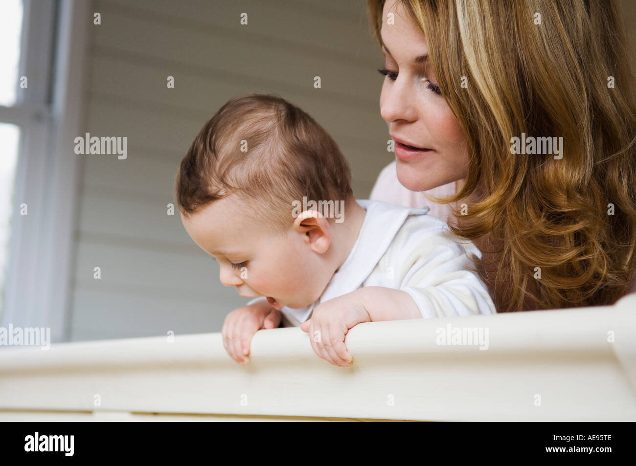 Woman and baby looking out of the window Stock Photo - Alamy