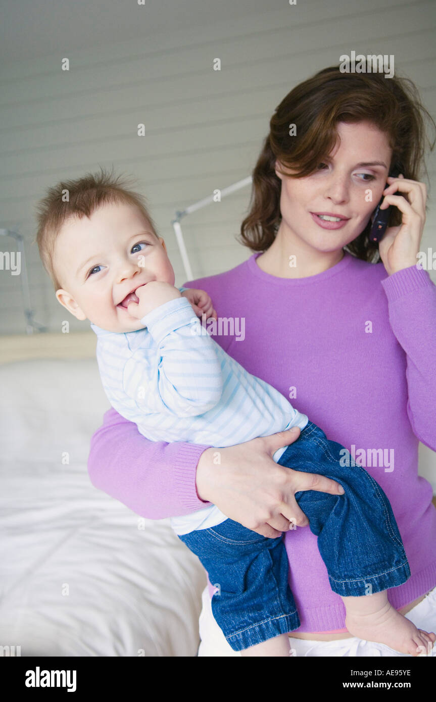 Mother holding her baby, phoning Stock Photo - Alamy