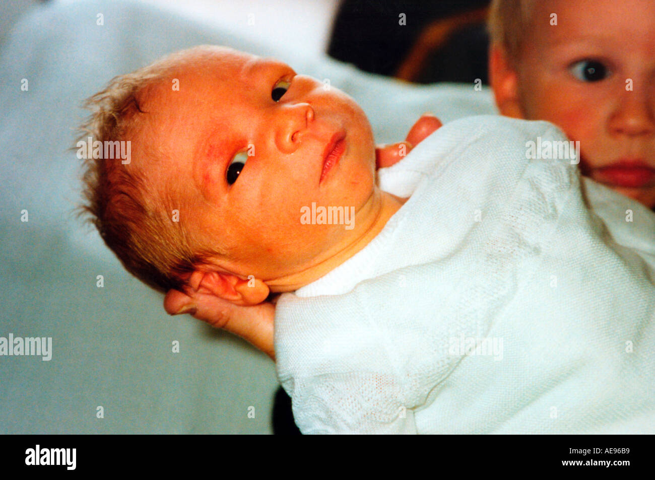 Newborn child cradled in arm with boy s face in background Stock Photo ...