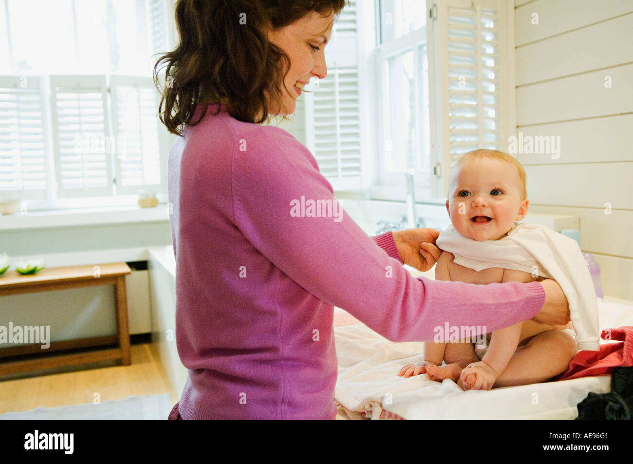 Mother dressing her baby Stock Photo - Alamy