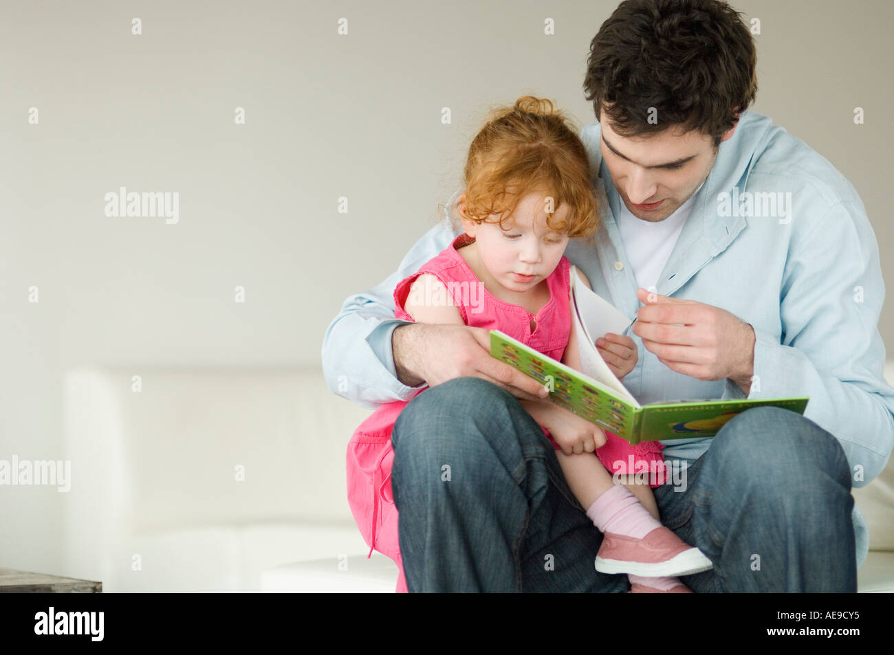 Man and little girl reading children's book Stock Photo - Alamy