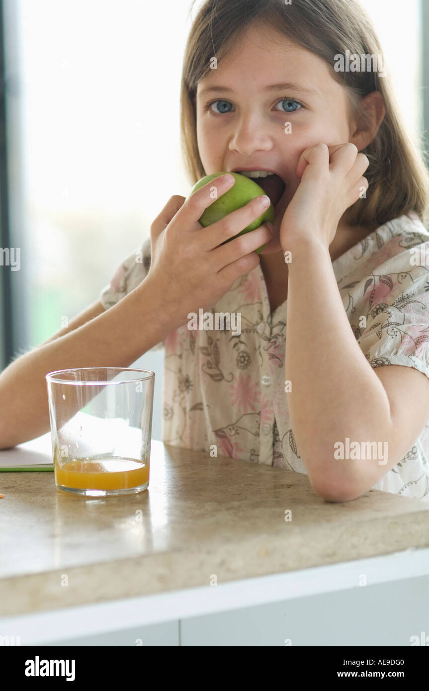 Portrait of a little girl eating an apple, looking at the camera Stock ...