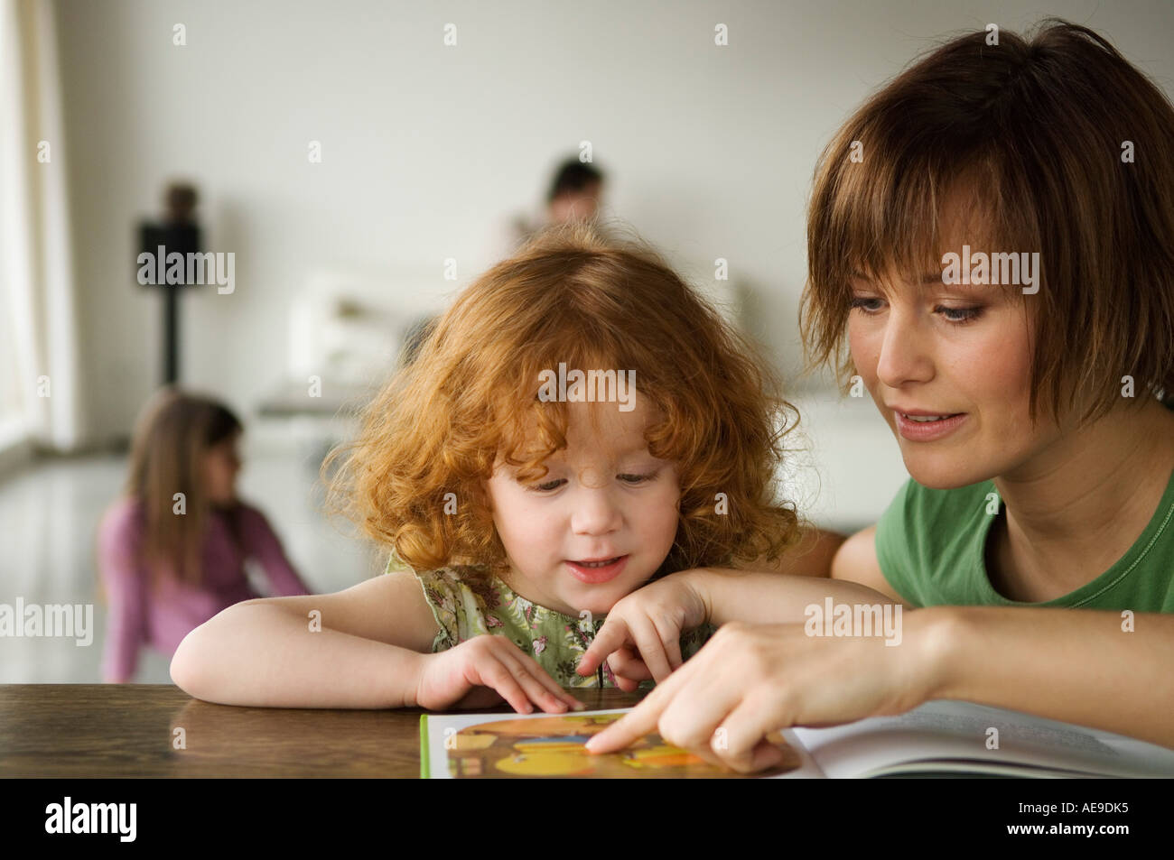 Little girl and woman reading children's book Stock Photo - Alamy