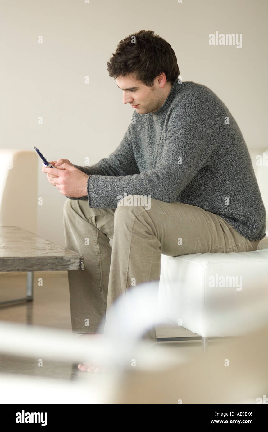 Man sitting on a sofa using a mobile phone Stock Photo - Alamy