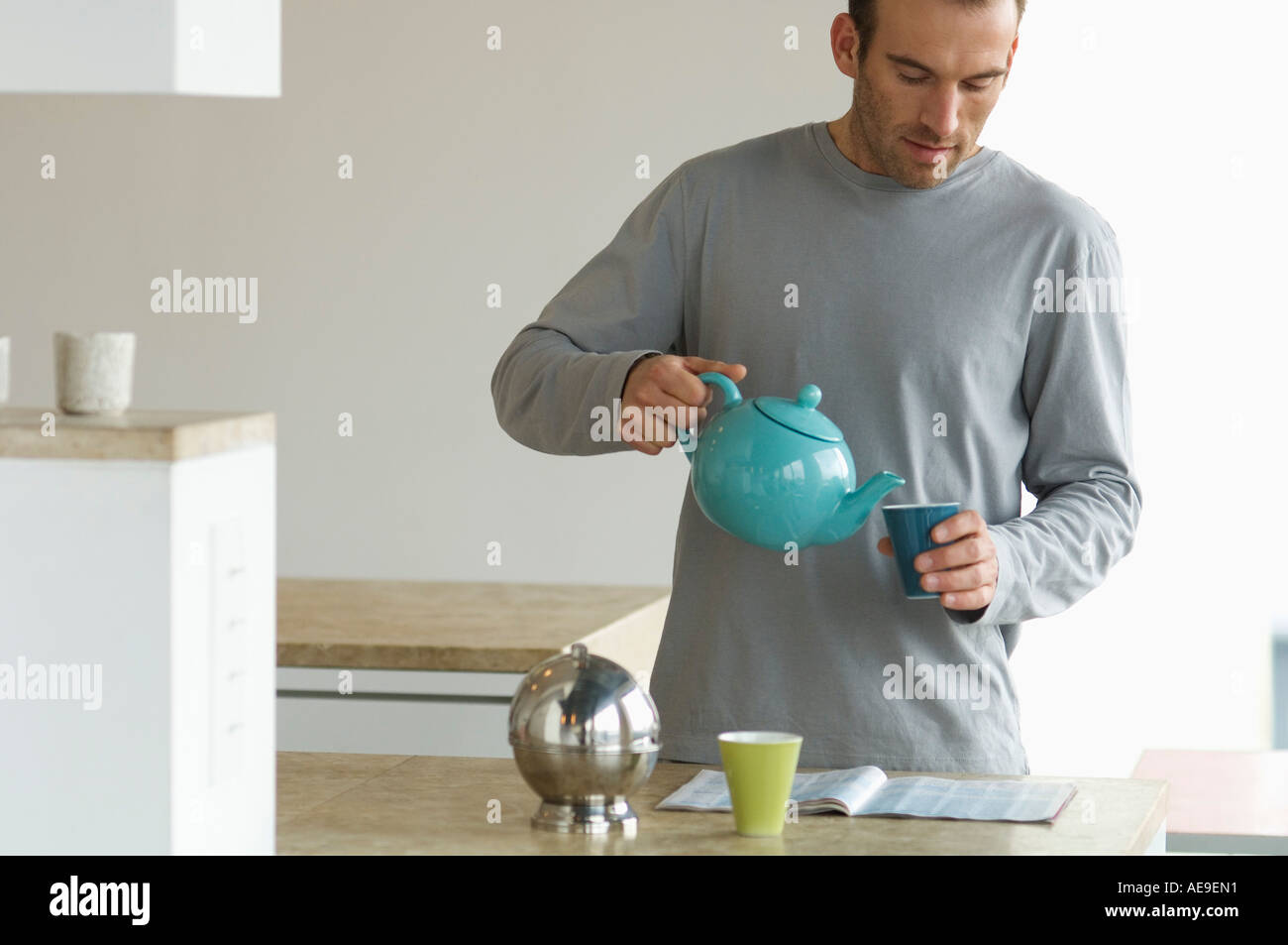 Man standing in the kitchen, pouring tea into a glass Stock Photo - Alamy