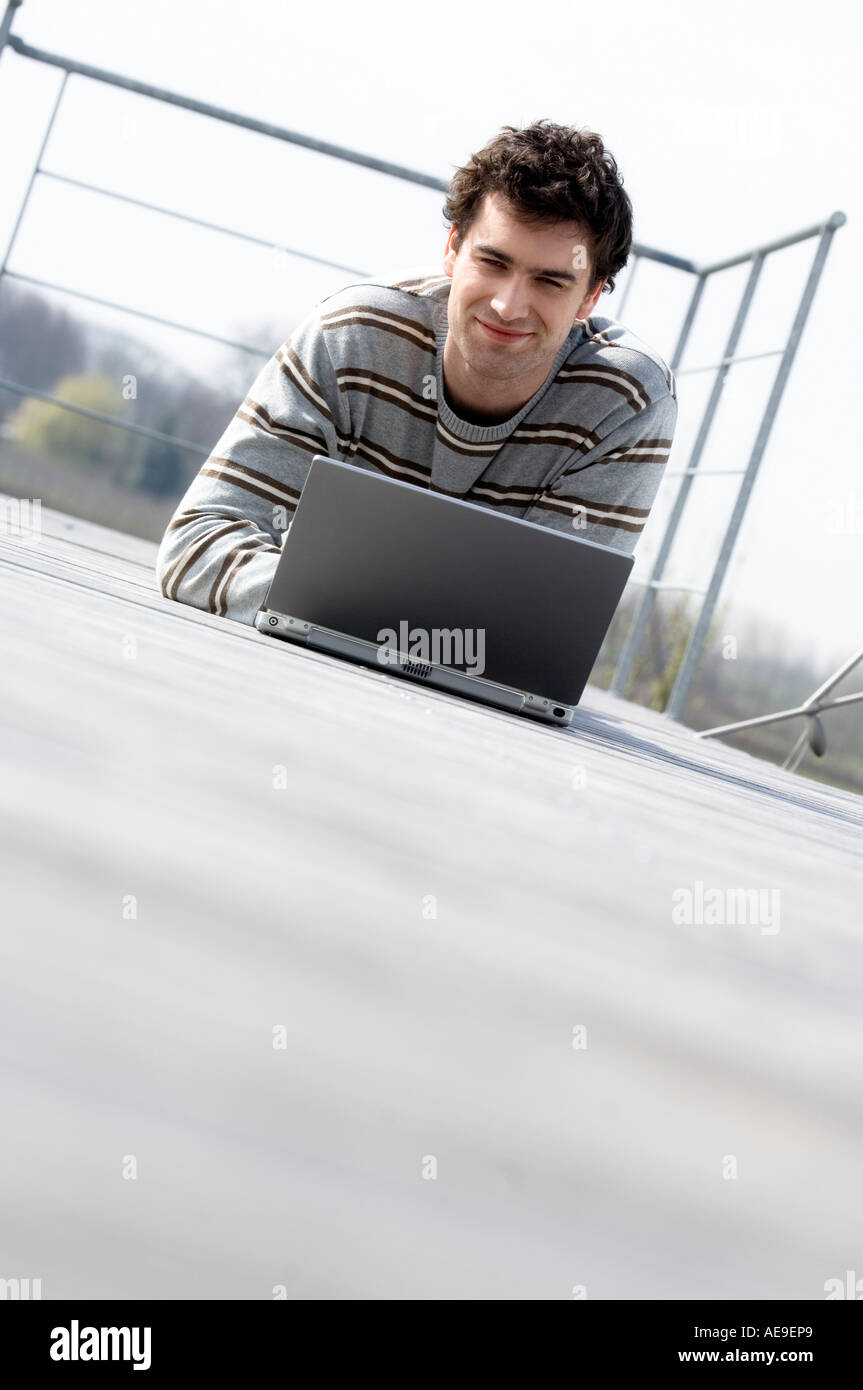 Man lying on a terrace using laptop computer Stock Photo - Alamy
