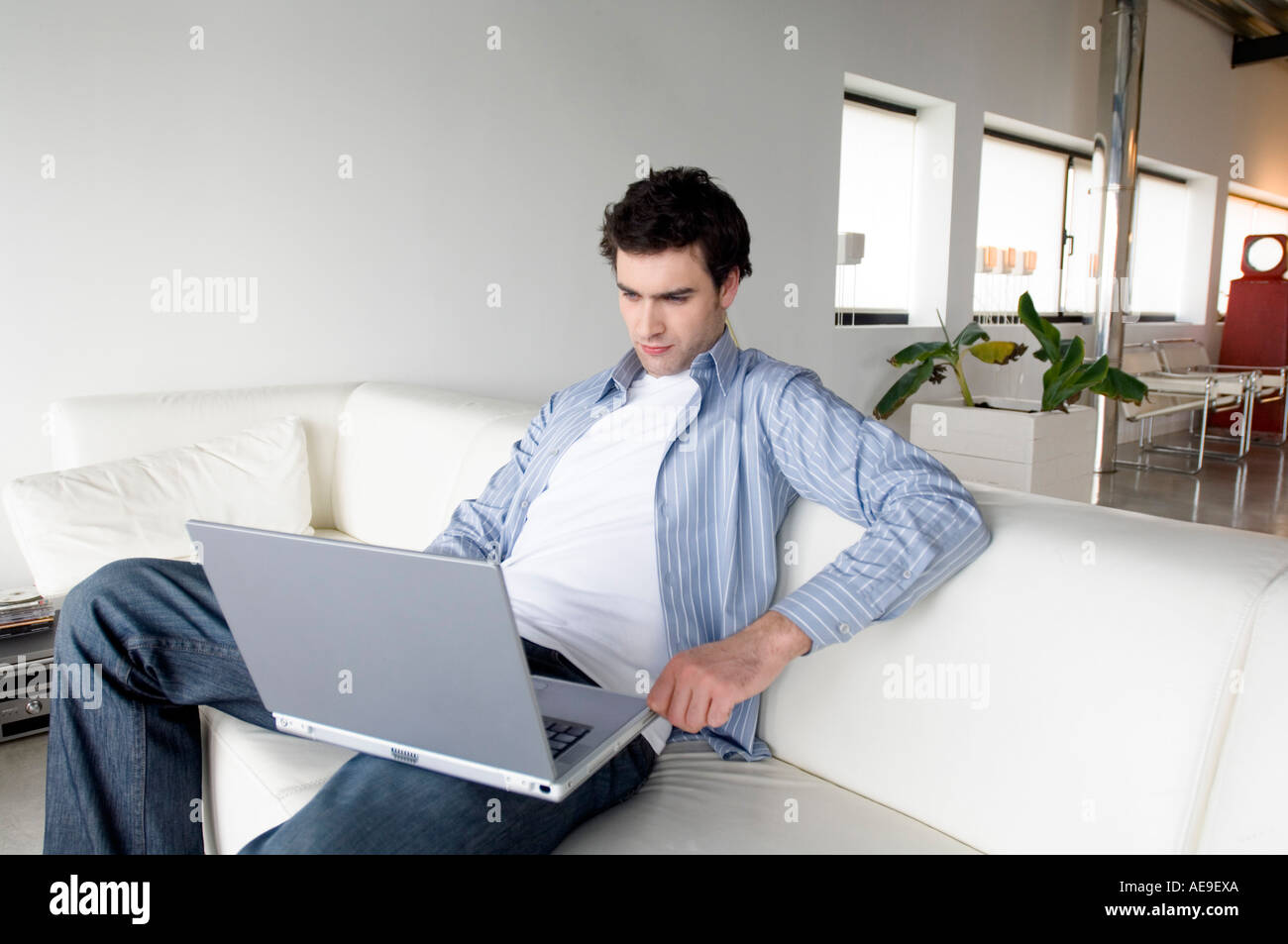 Man sitting on a sofa using laptop computer Stock Photo - Alamy