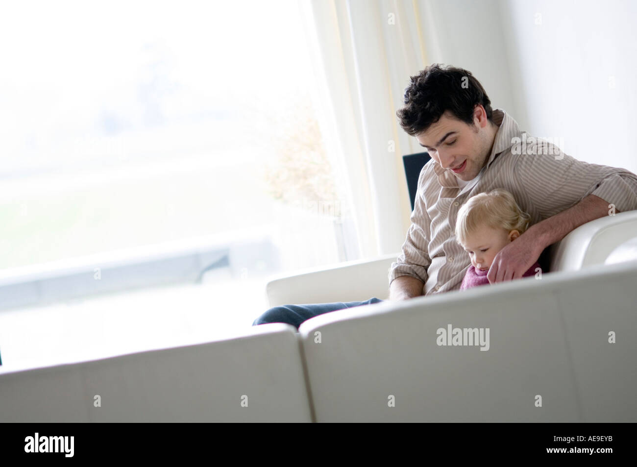 Man and little boy sitting on a sofa in a living-room Stock Photo - Alamy