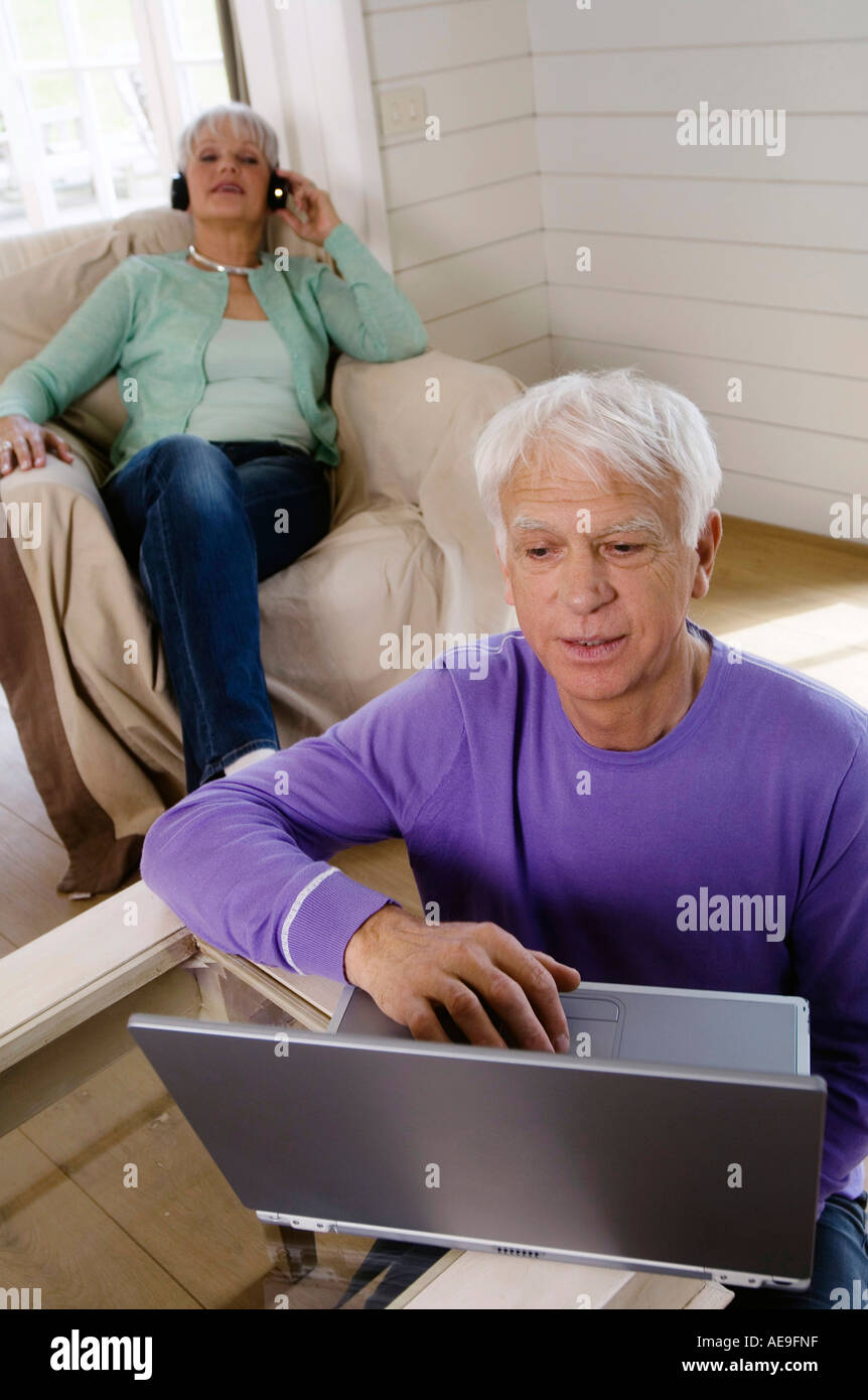Senior couple in the living-room, man using laptop computer, woman ...