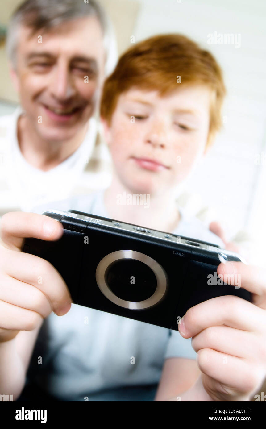 Senior man and boy playing Playstation Portable Stock Photo - Alamy
