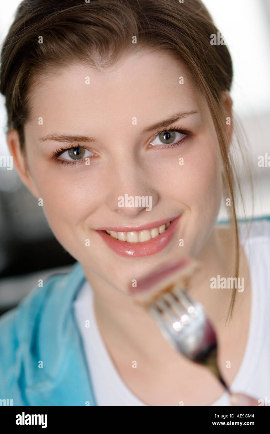 Portrait of a young smiling woman eating meat Stock Photo - Alamy