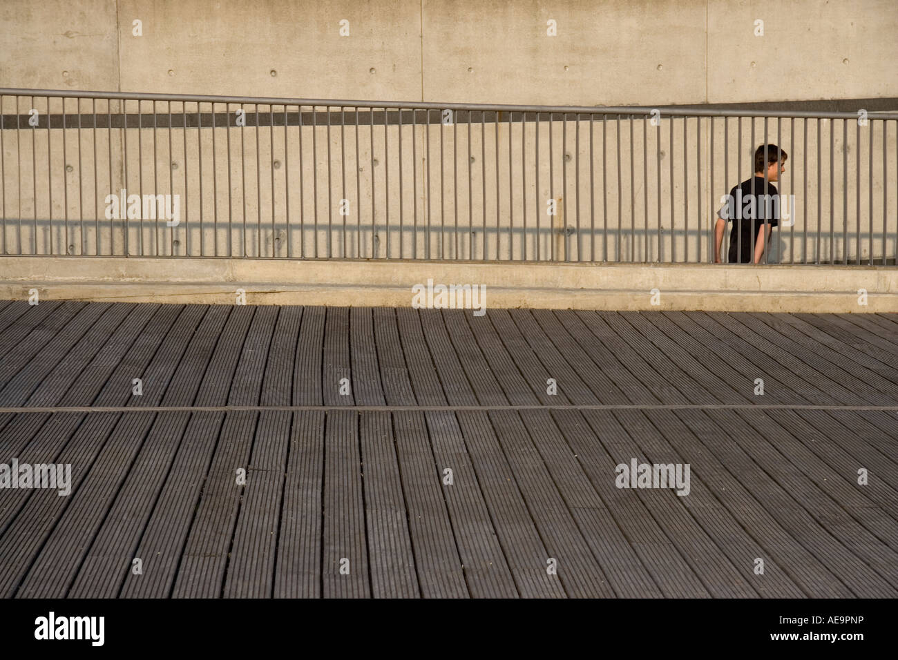 A man walking behind a metal railing fence in a modern environmet with ...