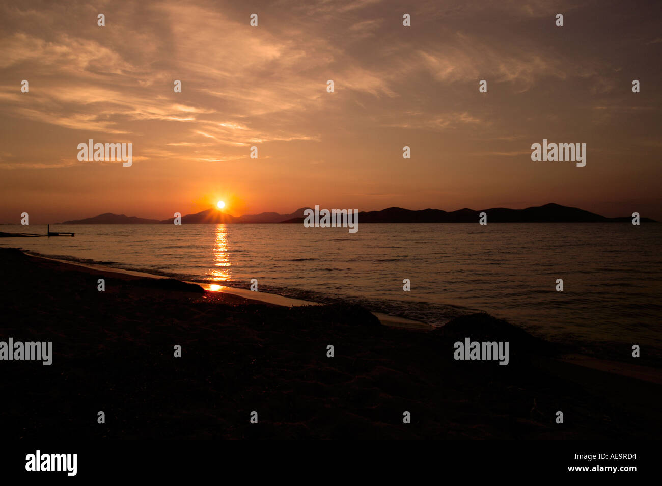 Sun setting over the Island of Nisyros as seen from Tigaki Beach on the ...