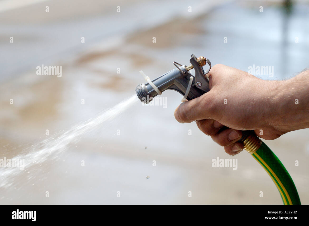 Mans hand spraying water from a garden hose Stock Photo - Alamy