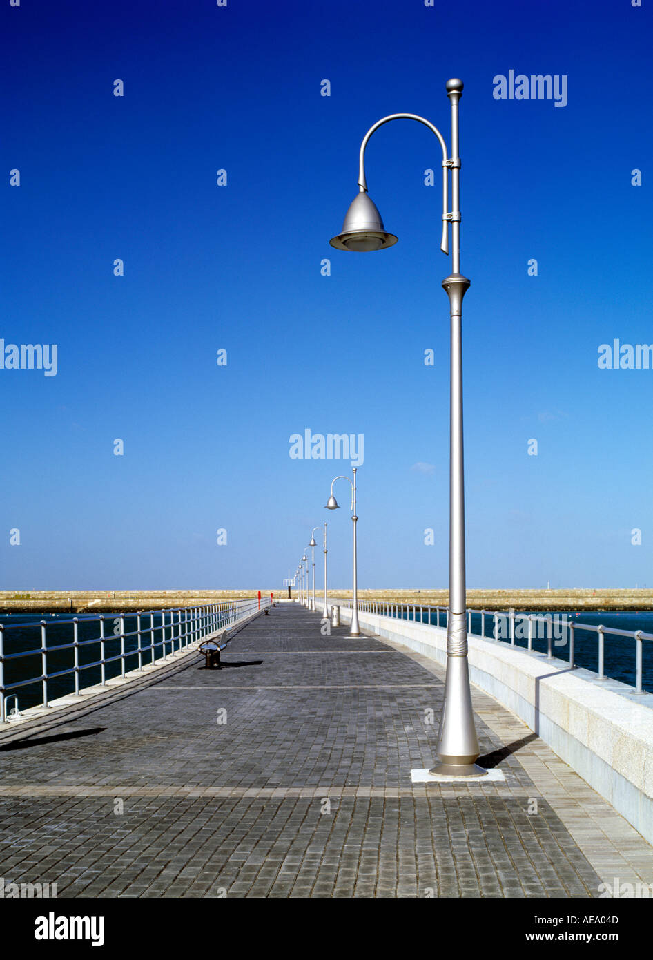 A line of street lamps lead off into the distance on a seaside ...